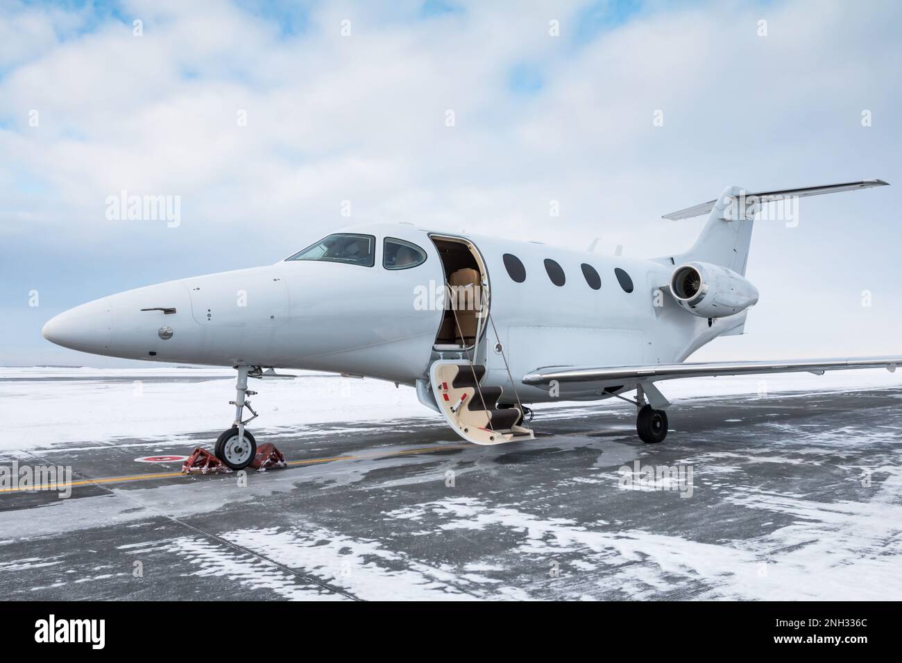 Modern white business jet with an opened gangway door at the winter ...