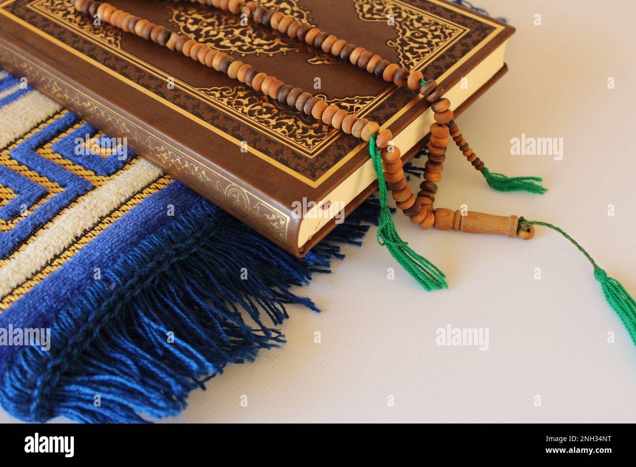 Holy quran and prayer rosary on prayer mat on white background. Islamic ...
