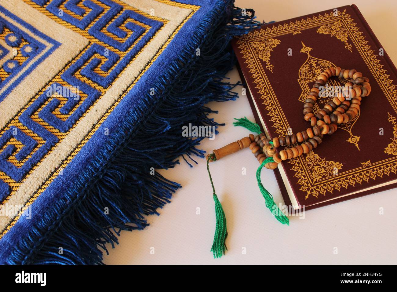 Holy quran and prayer rosary on prayer mat on white background. Islamic ...