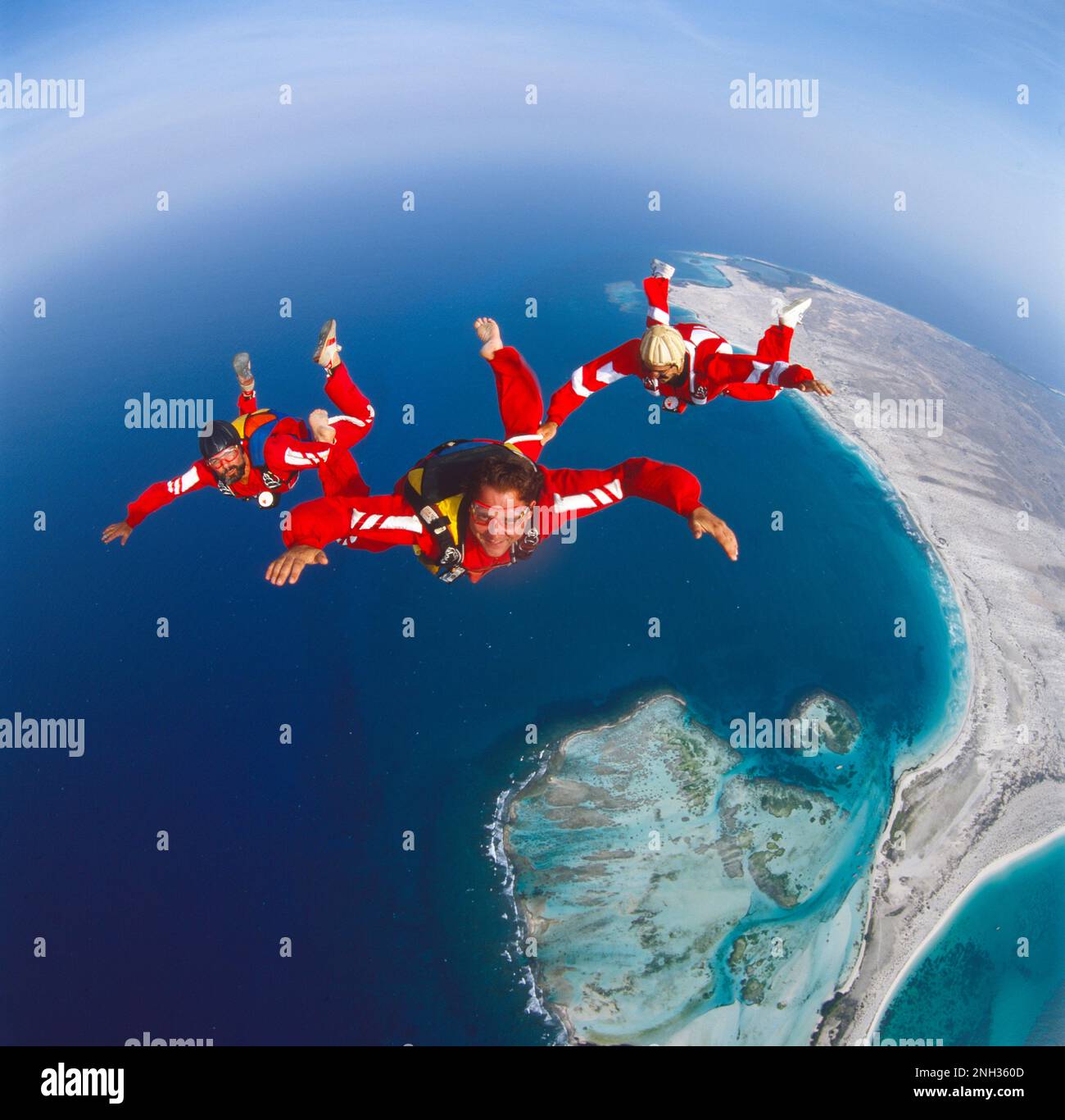 Three. Sky divers freefalling and formation over land and sea Stock ...