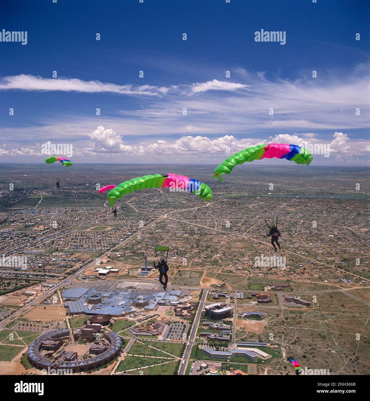 Longshot of 4 parachutists with their chutes open falling towards the ...