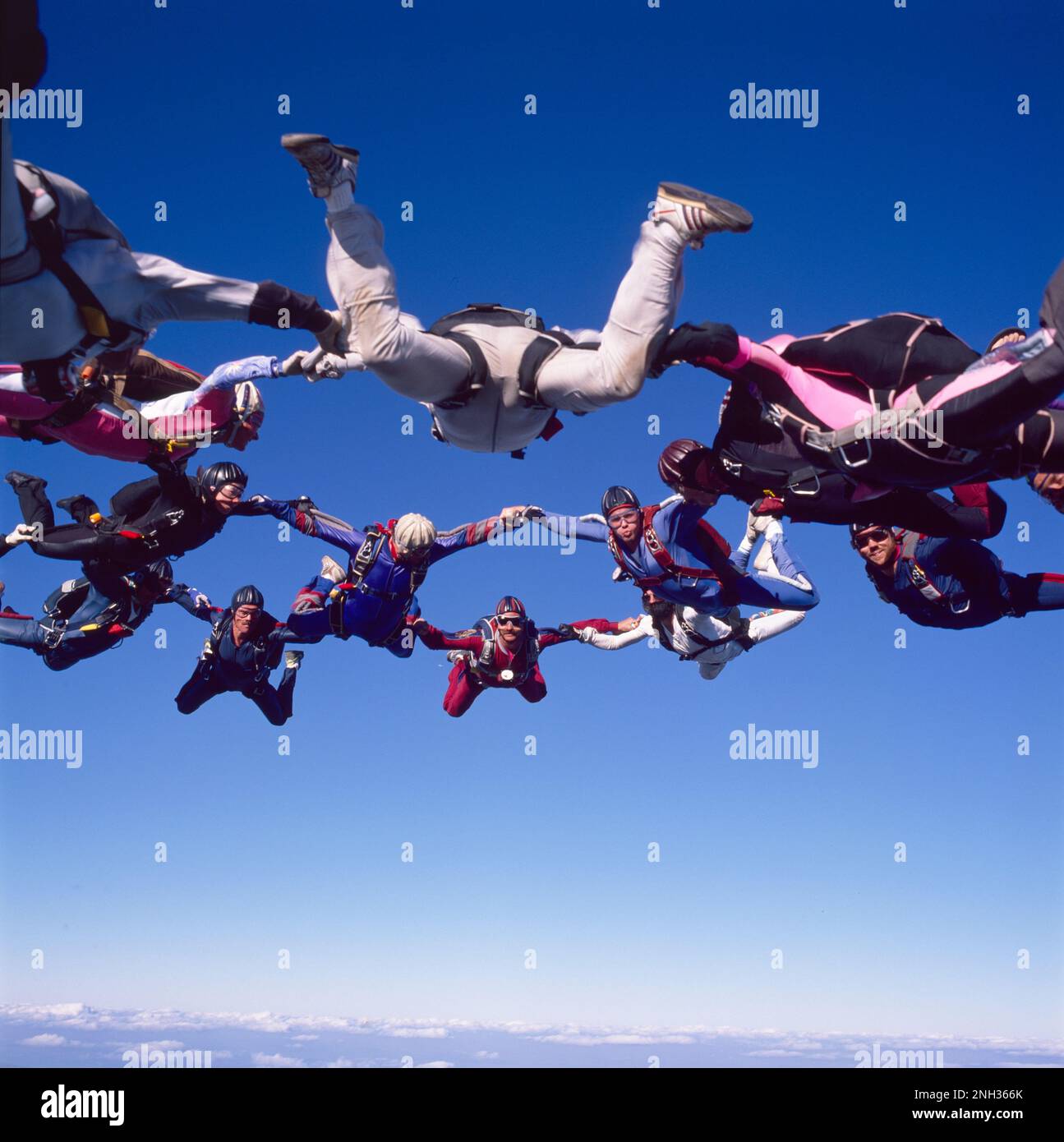 Image shot from below, looking up at group of skydivers holding hands ...