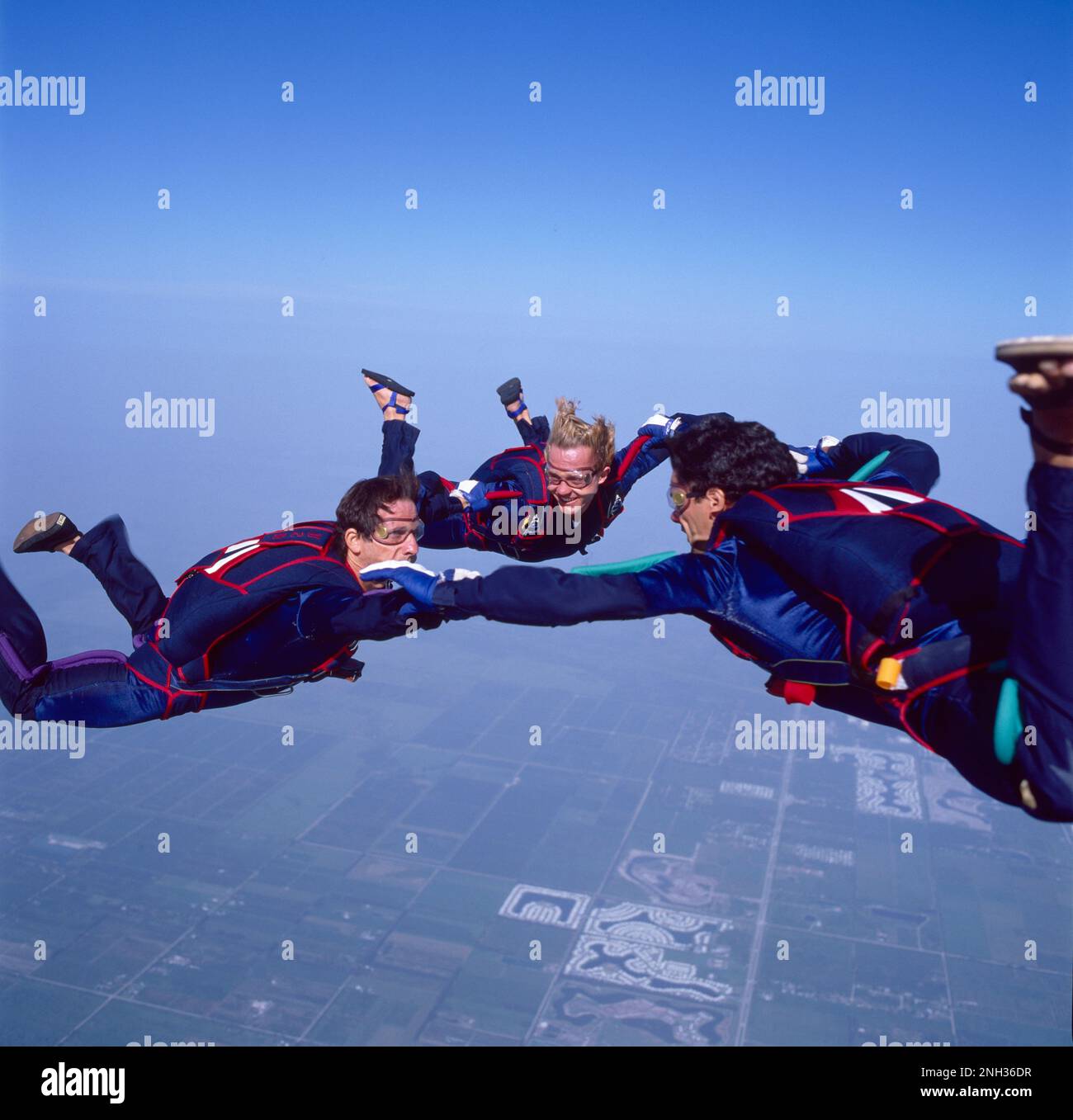 3 skydivers in a free-fall holding hands in a formation Stock Photo - Alamy
