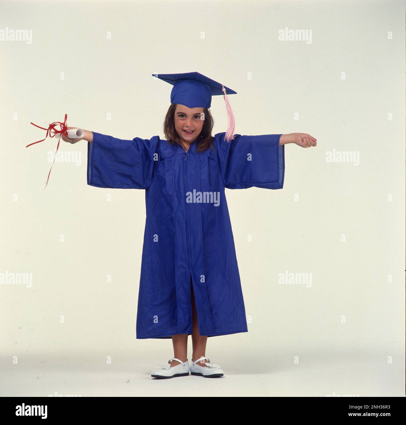 Young Girl in a blue graduate cap and gown holding a diploma with her ...