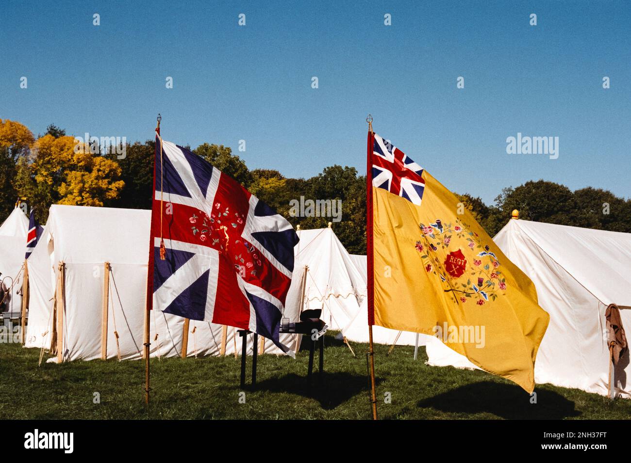 Colonial era British flags sway in the wind in front of a camp of ...