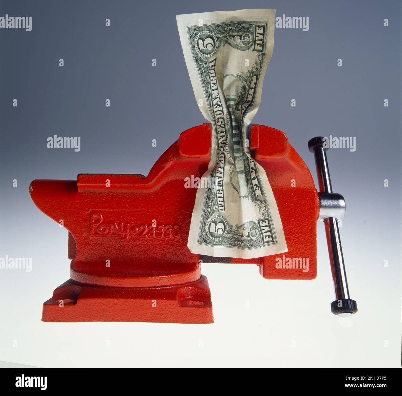 Symbolic image of the US five dollar bill being squeezed in a vice ...