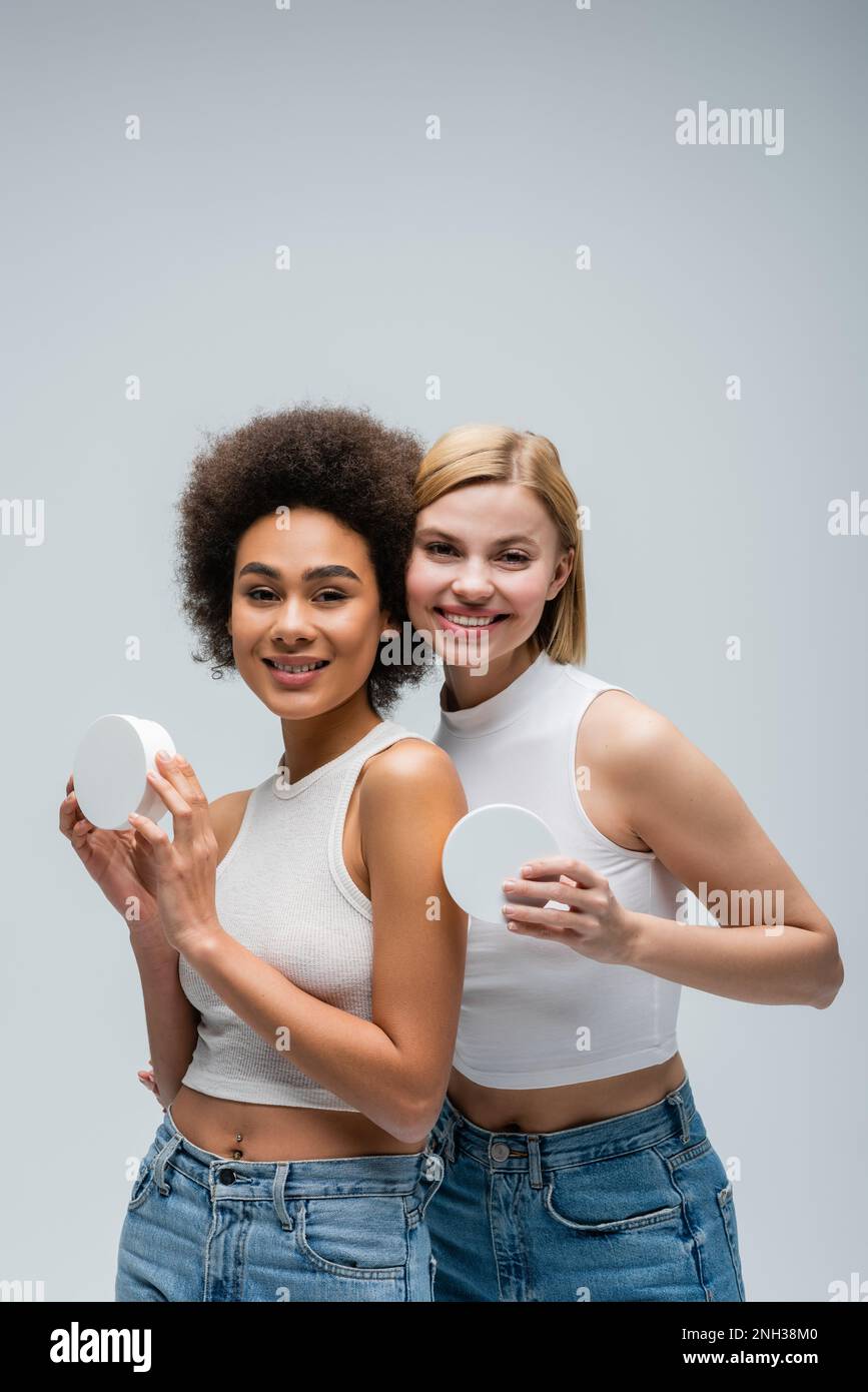 pretty multiethnic models in white tank tops posing with containers of ...