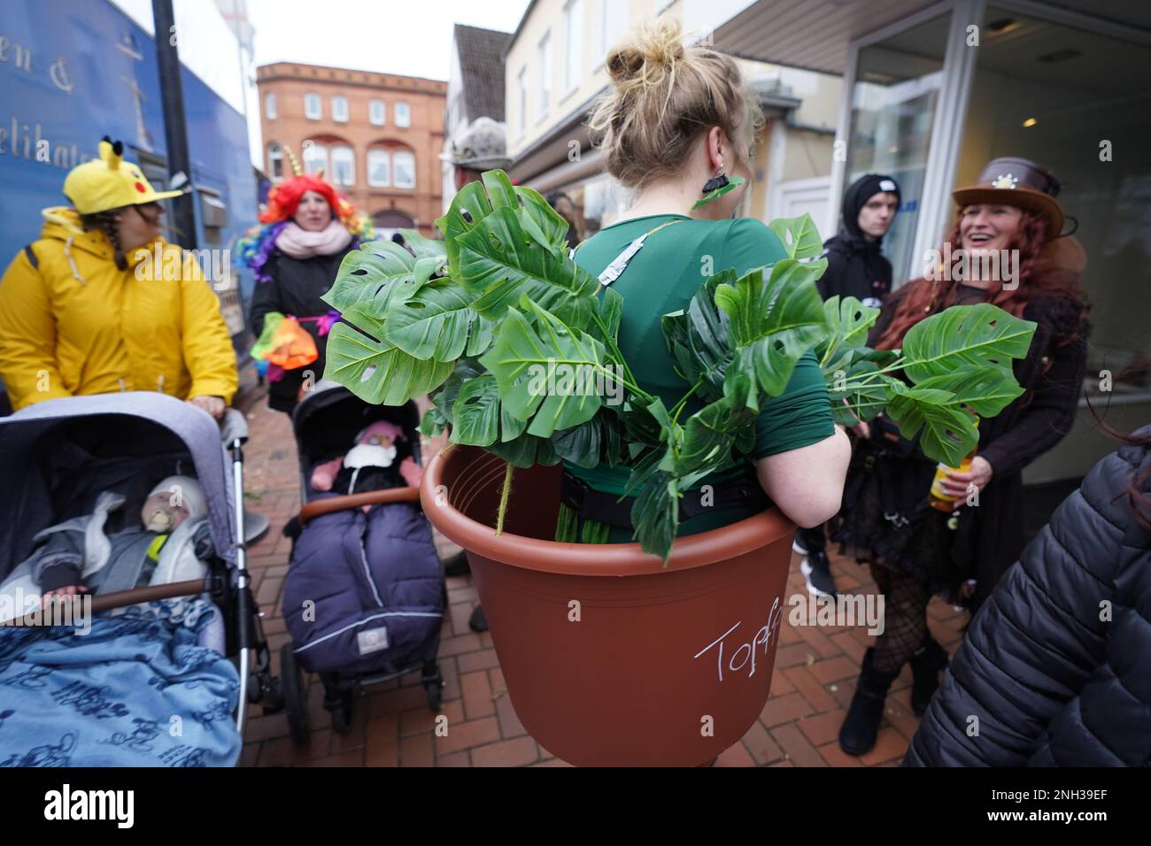 Marne, Germany. 20th Feb, 2023. A woman dressed as a potted plant walks ...