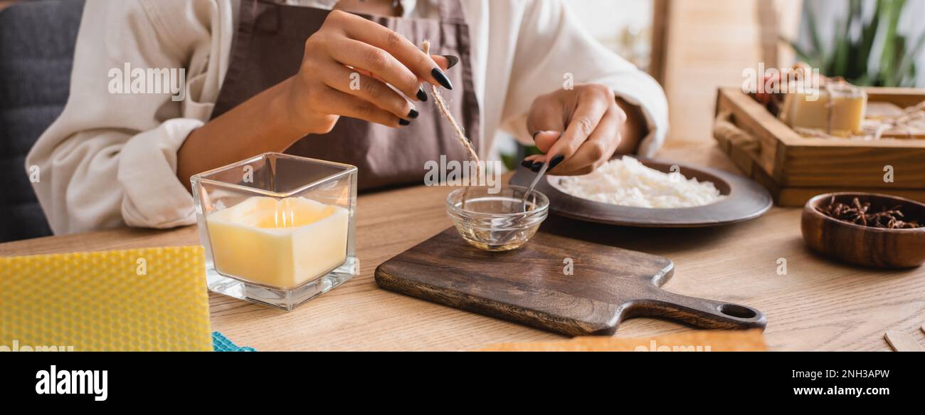 partial view of african american craftswoman dipping rope in melted ...