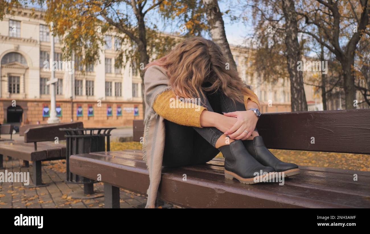A young girl crying on a park bench in the fall Stock Photo - Alamy