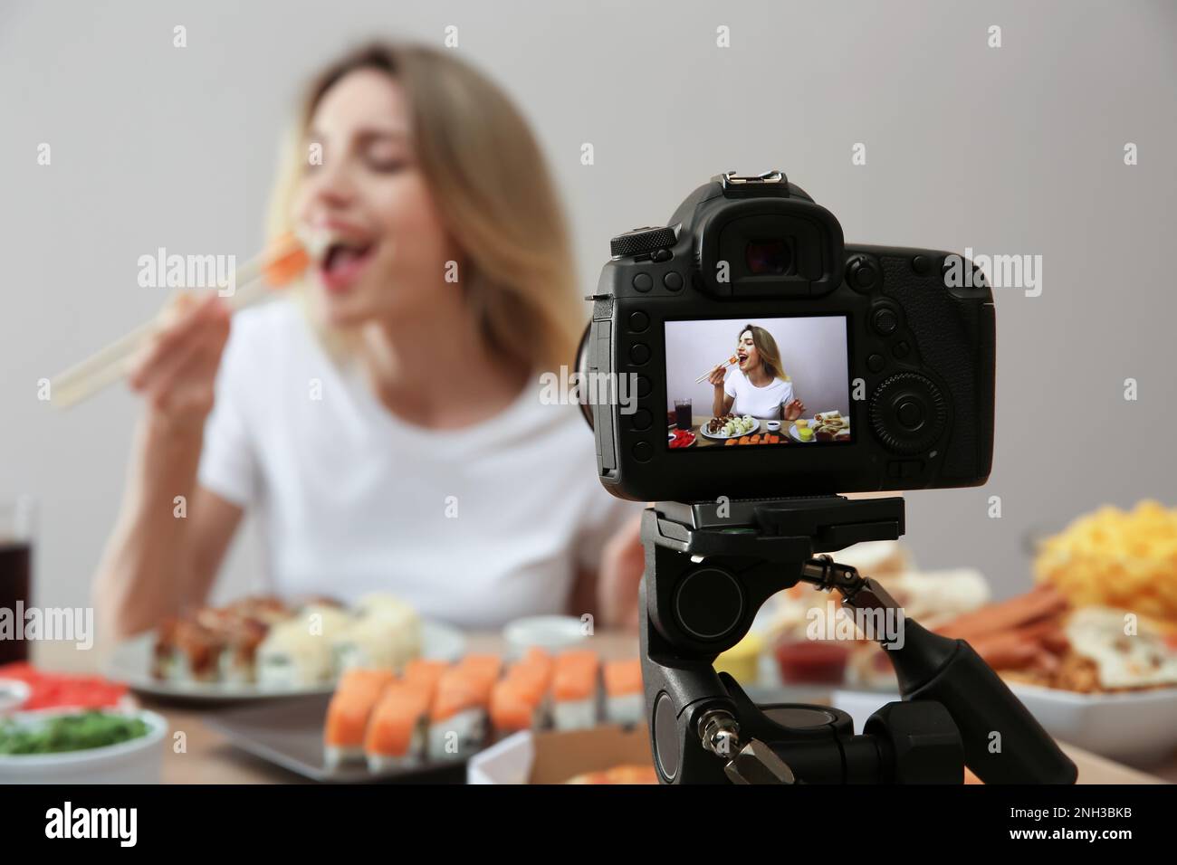 Food blogger recording eating show against beige background, focus on ...