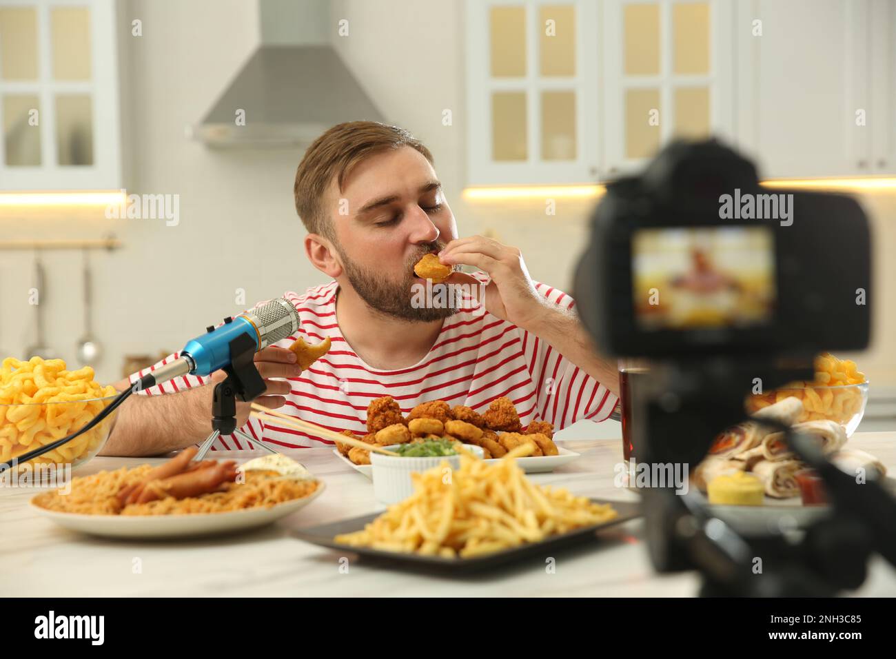 Food blogger recording eating show on camera in kitchen. Mukbang vlog ...