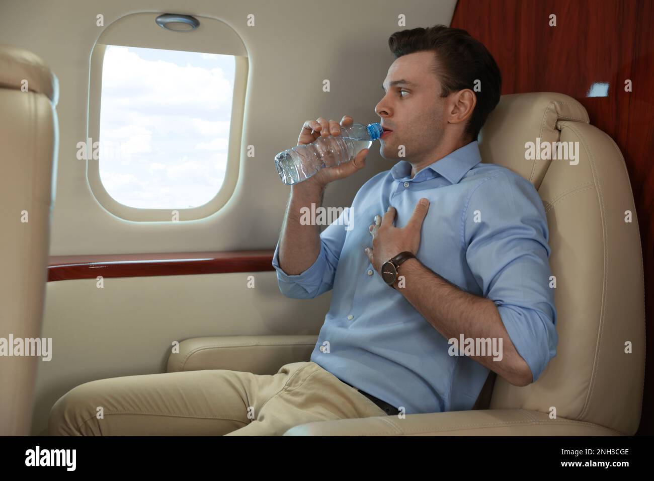 Nervous young man with aviophobia drinking water in airplane Stock ...