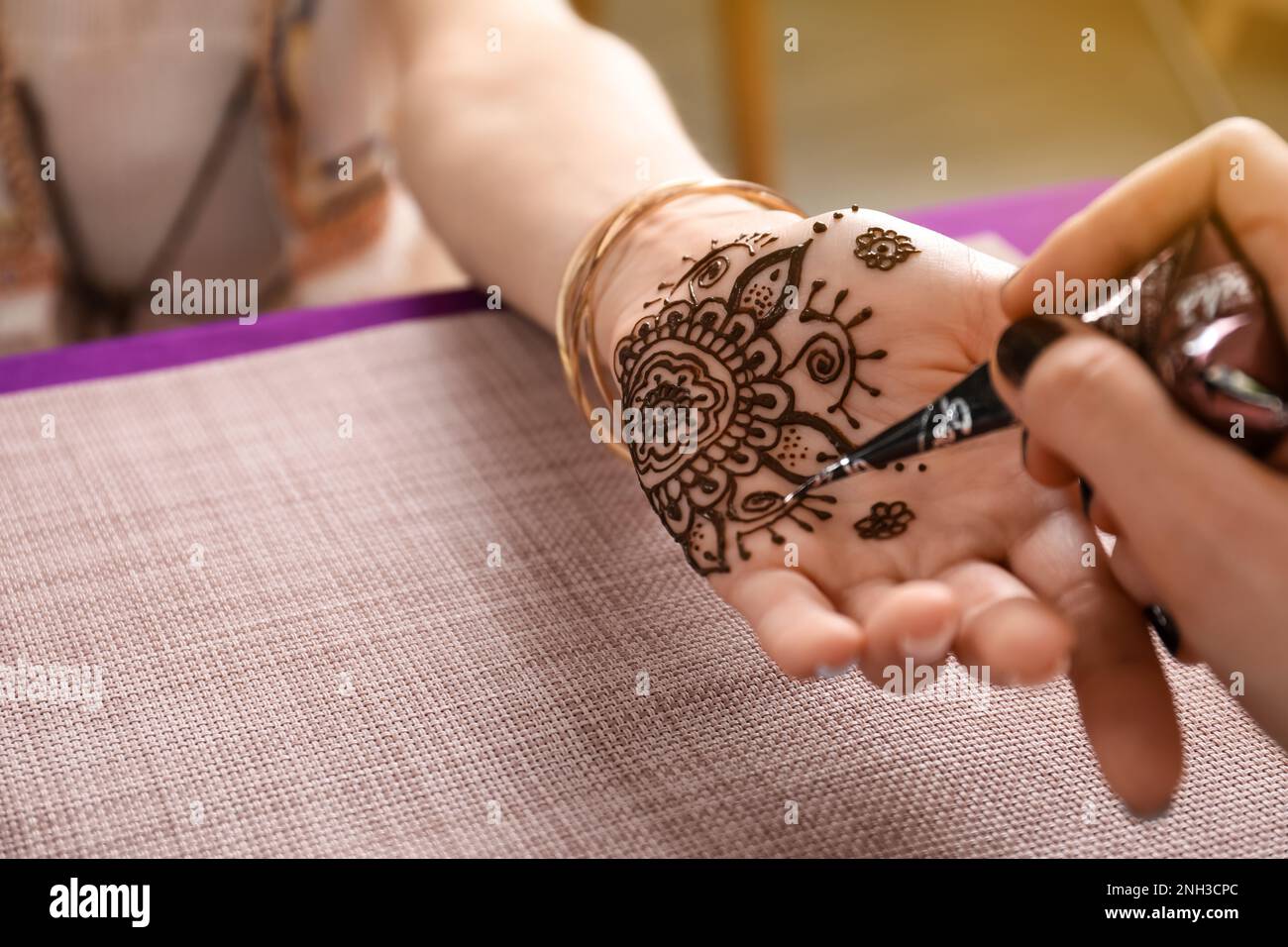 Professional mehndi master making henna tattoo at table, closeup. Space ...