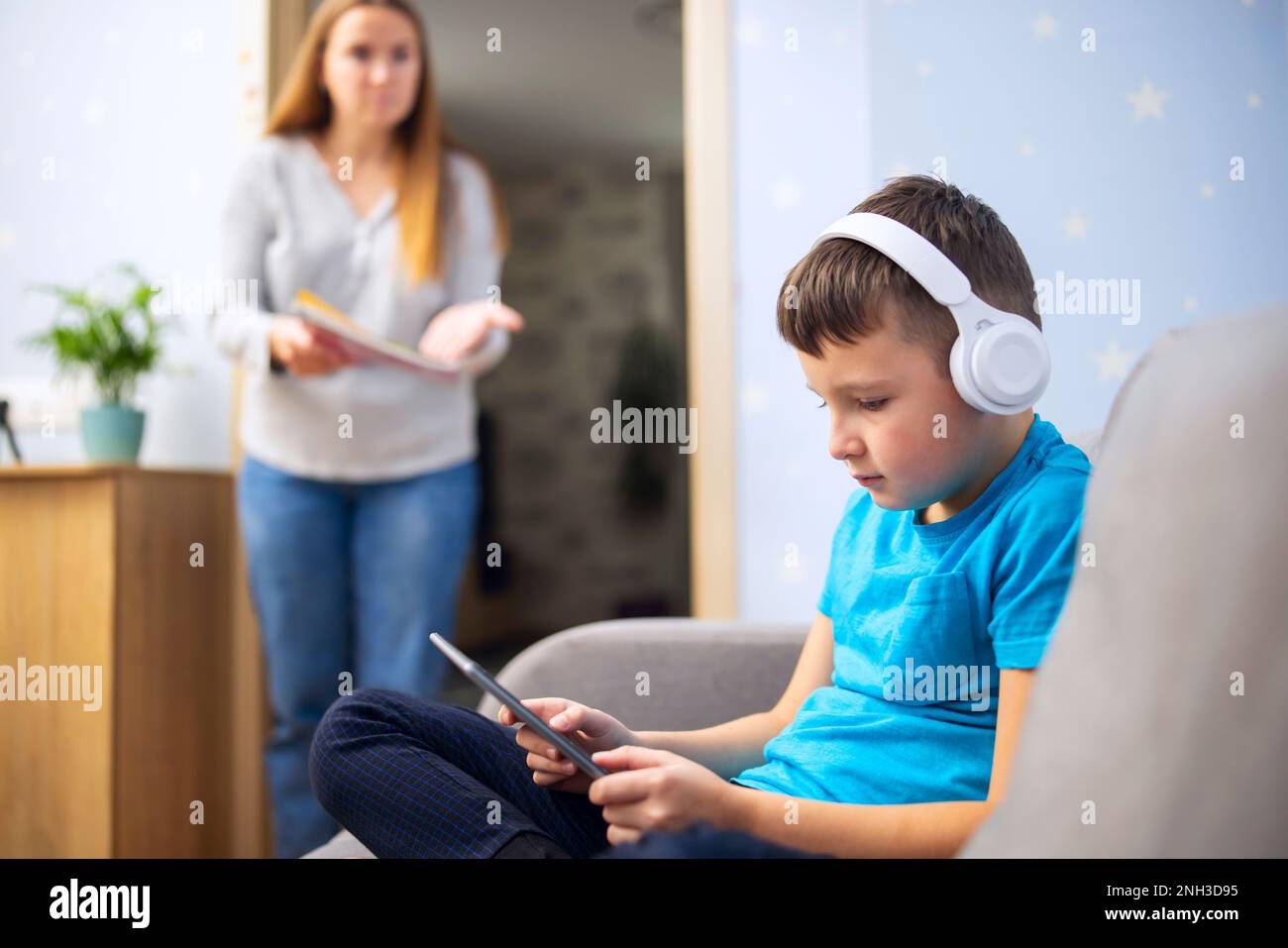 Mother scolds her son. Boy uses tablet with headphones and ignores his ...