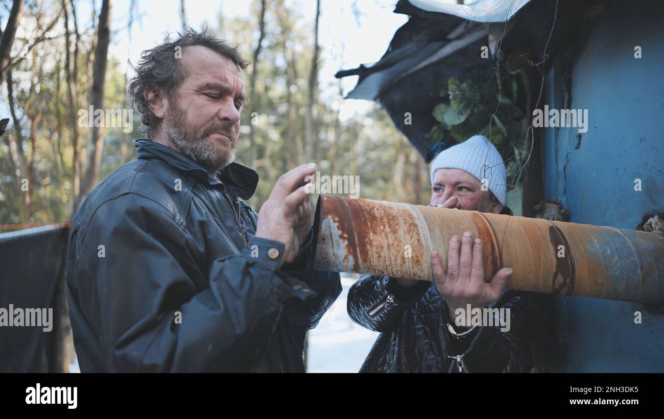 Homeless people warming their hands on the chimney of their hut in ...