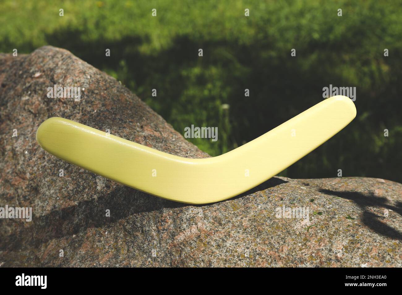 Sunlit yellow wooden boomerang on stone outdoors Stock Photo - Alamy