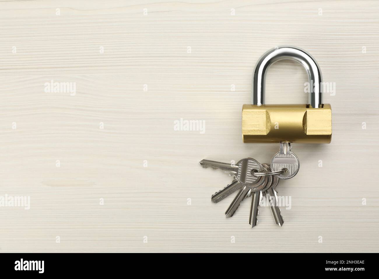 Modern padlock with keys on white wooden table, top view. Space for ...