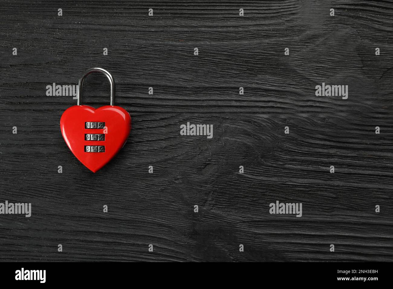 Red heart shaped combination lock on black wooden table, top view ...