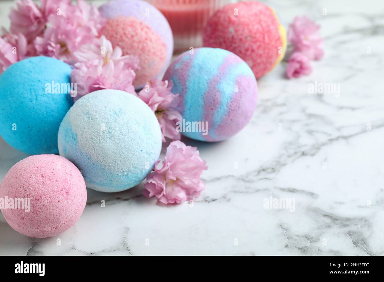 Fragrant bath bombs and sakura flowers on white marble table, closeup ...