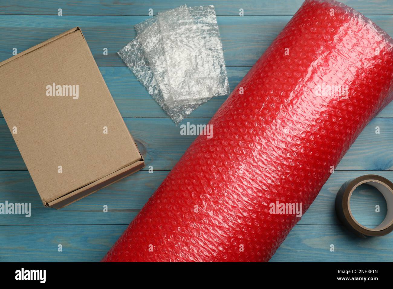 Flat lay composition with bubble wrap roll on light blue background ...
