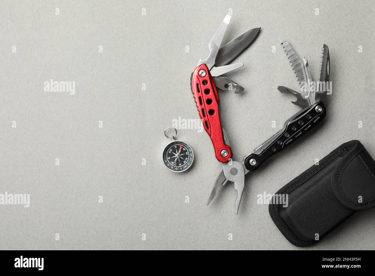 Compact portable multitool, case and compass on light grey background ...