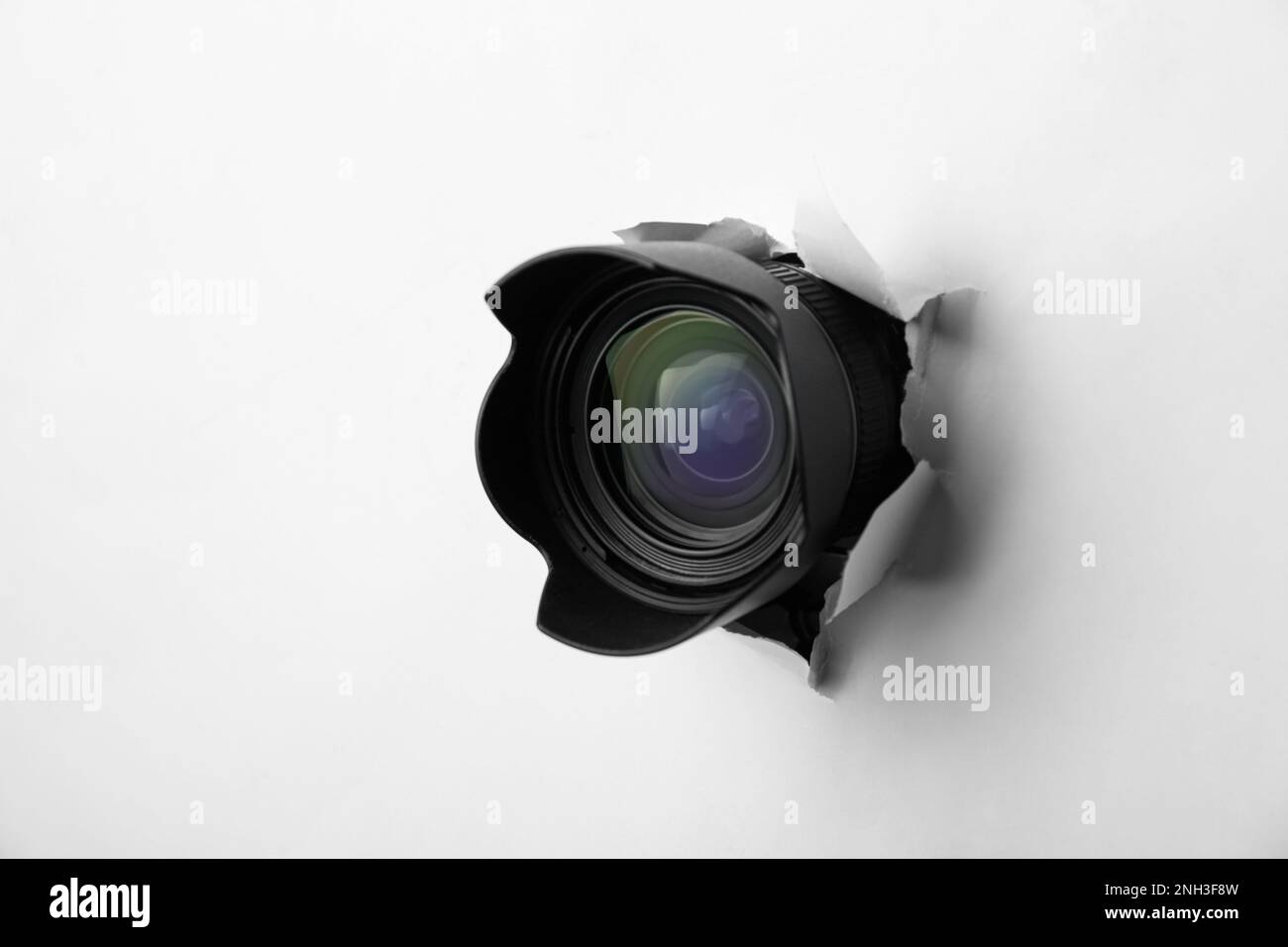 Hidden camera lens through torn hole in white paper Stock Photo - Alamy