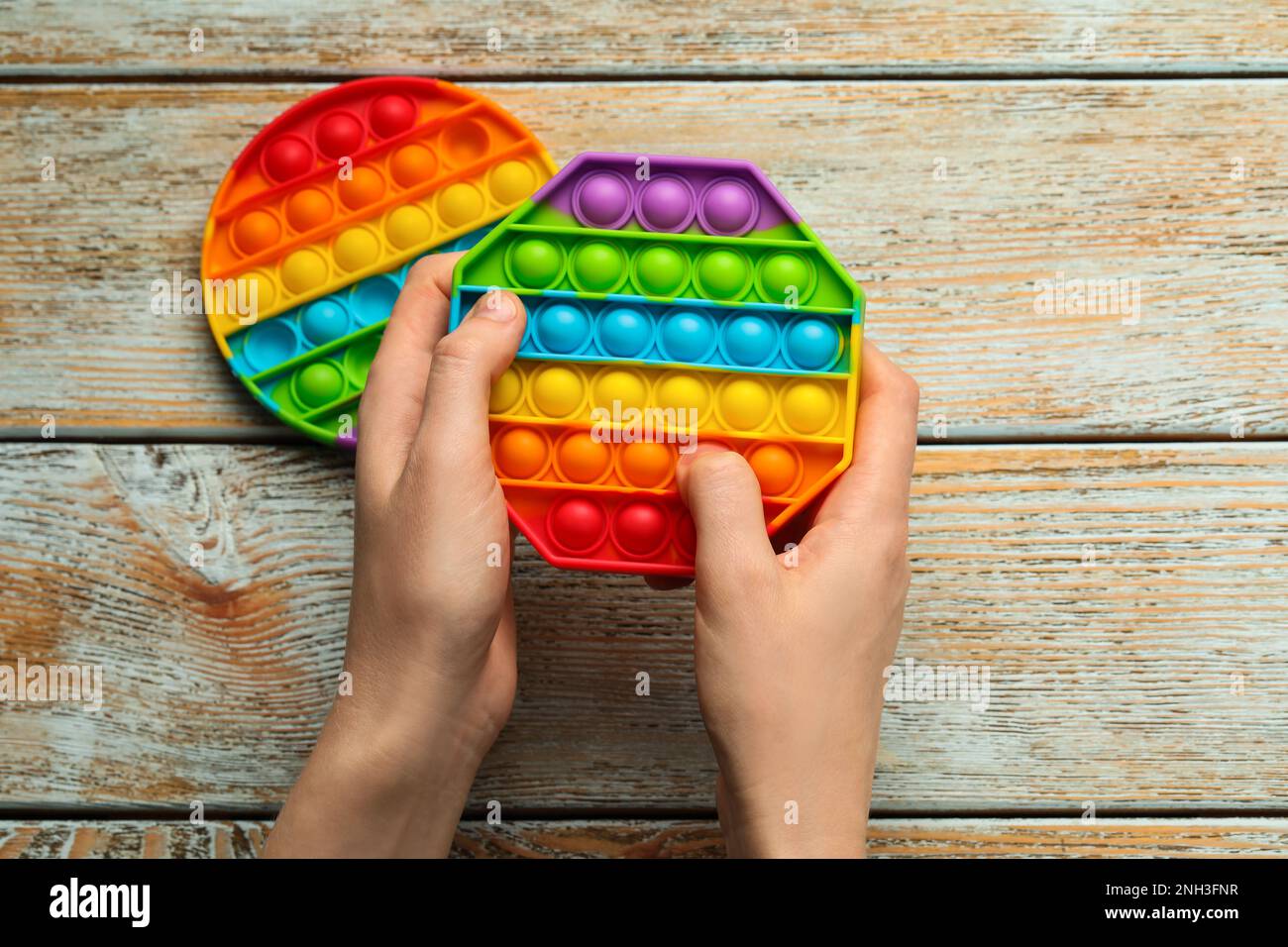Woman using pop it fidget toy at light wooden table, top view Stock ...