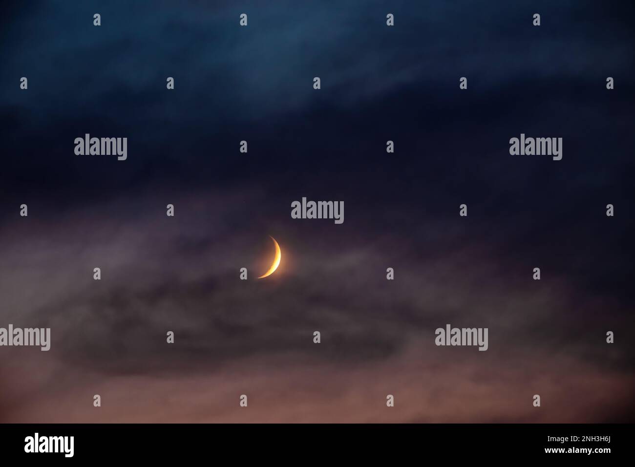 Rising Moon. A crescent moon in the dark cloudy night sky Stock Photo ...