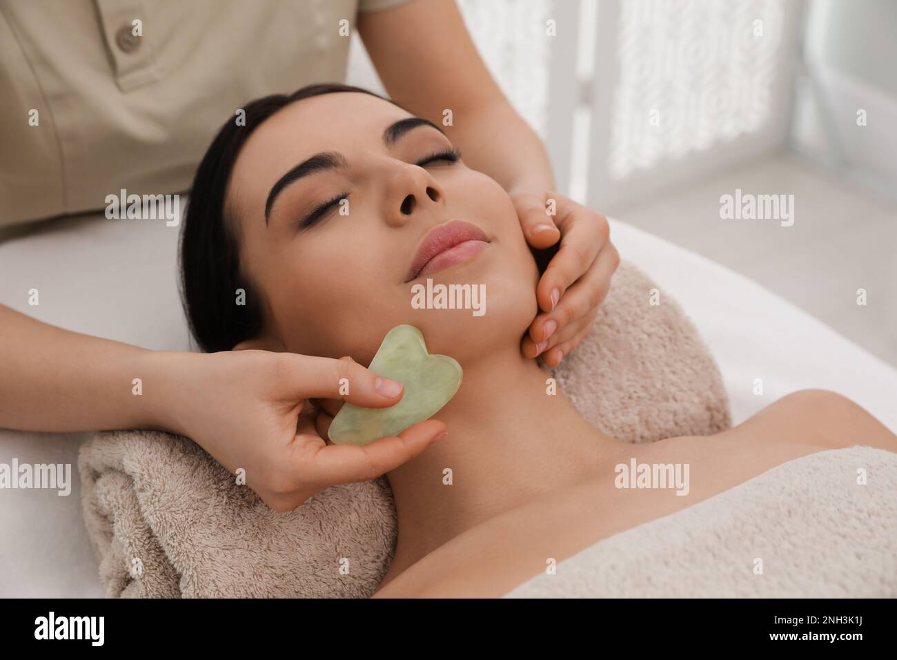 Young woman receiving facial massage with gua sha tool in beauty salon Stock Photo - Alamy