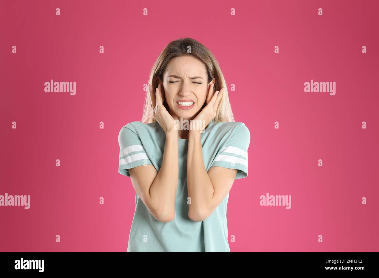 Emotional young woman covering her ears on pink background Stock Photo ...