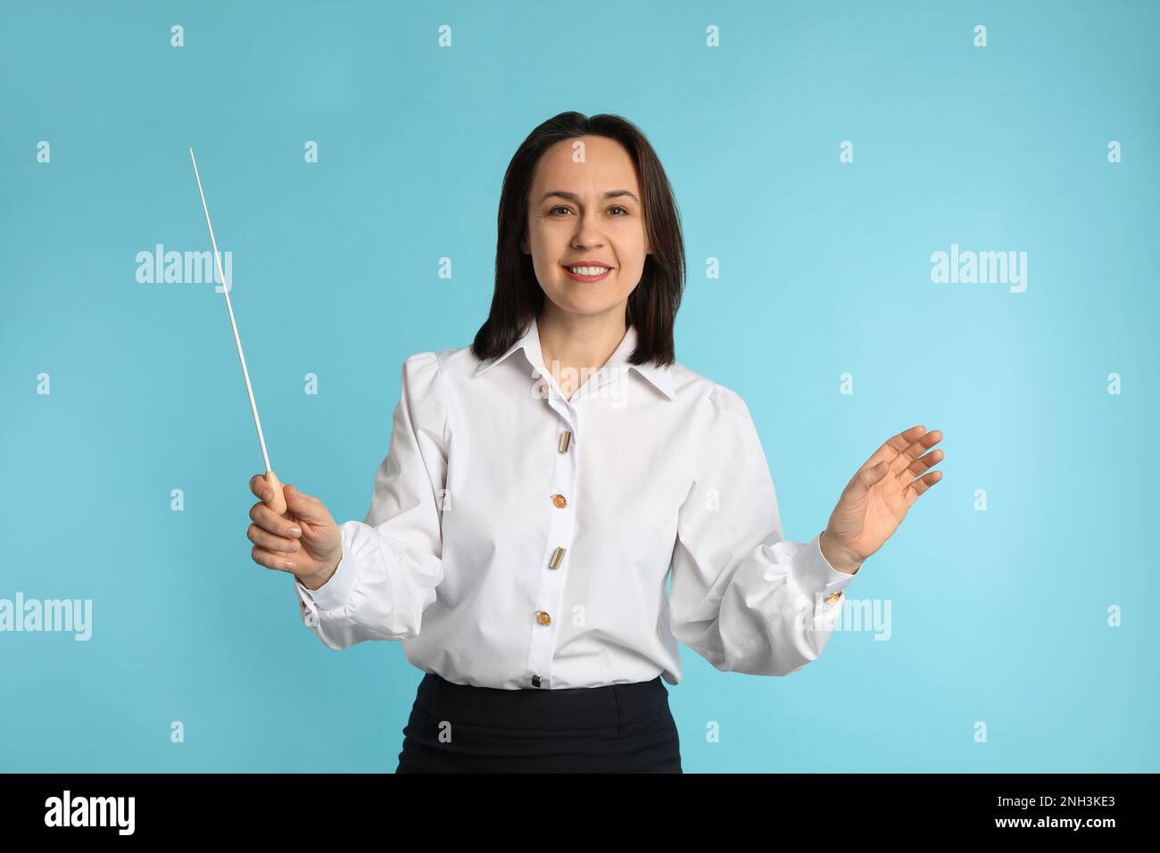 Music teacher with baton on turquoise background Stock Photo - Alamy