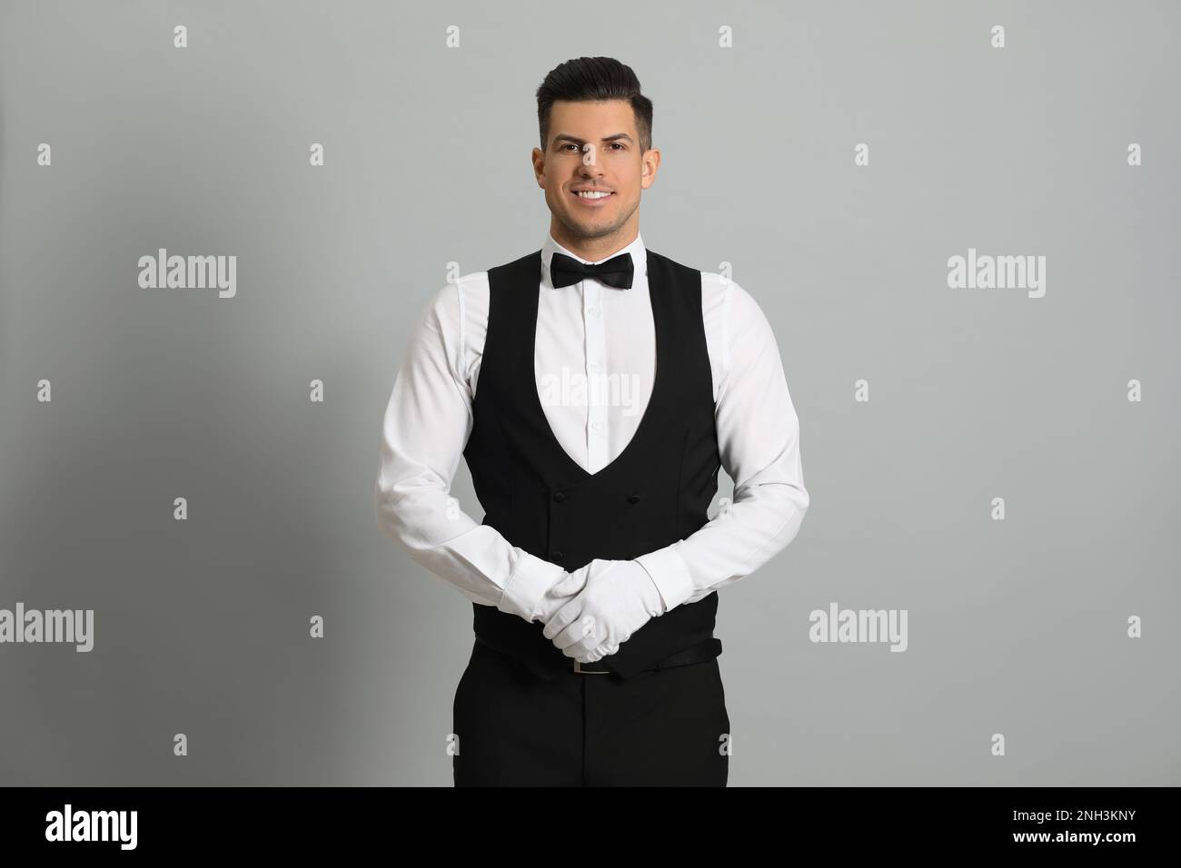 Handsome butler in elegant uniform on grey background Stock Photo - Alamy