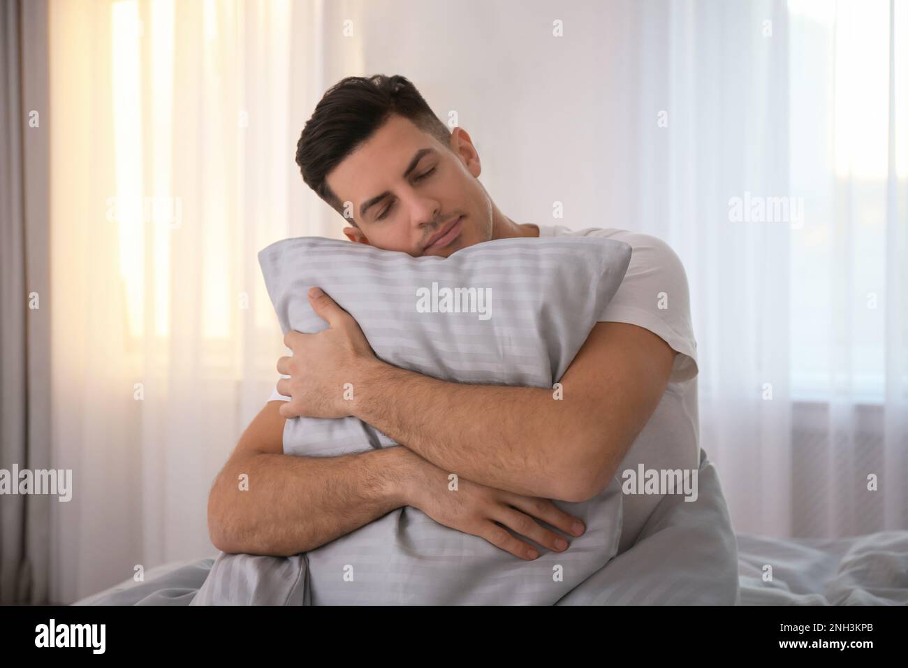 Man hugging pillow on bed hi-res stock photography and images - Alamy