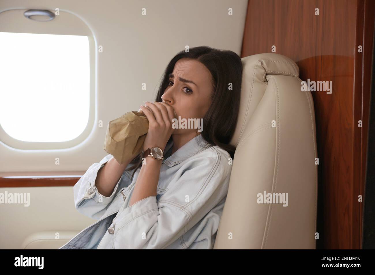 Nervous young woman with aviophobia breathing into paper bag in ...