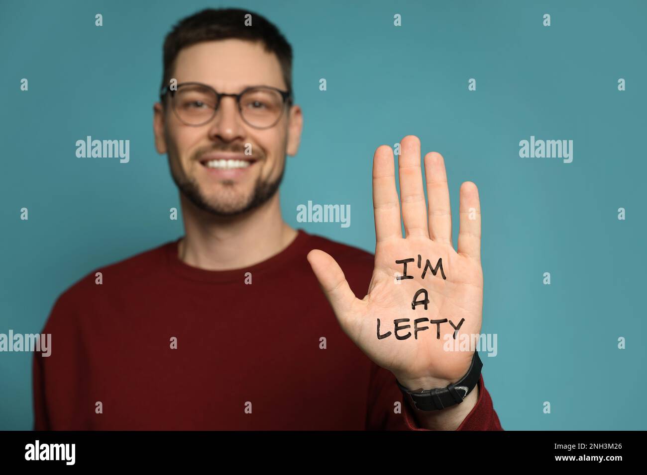 Left-handed man against light blue background, focus on palm with text ...