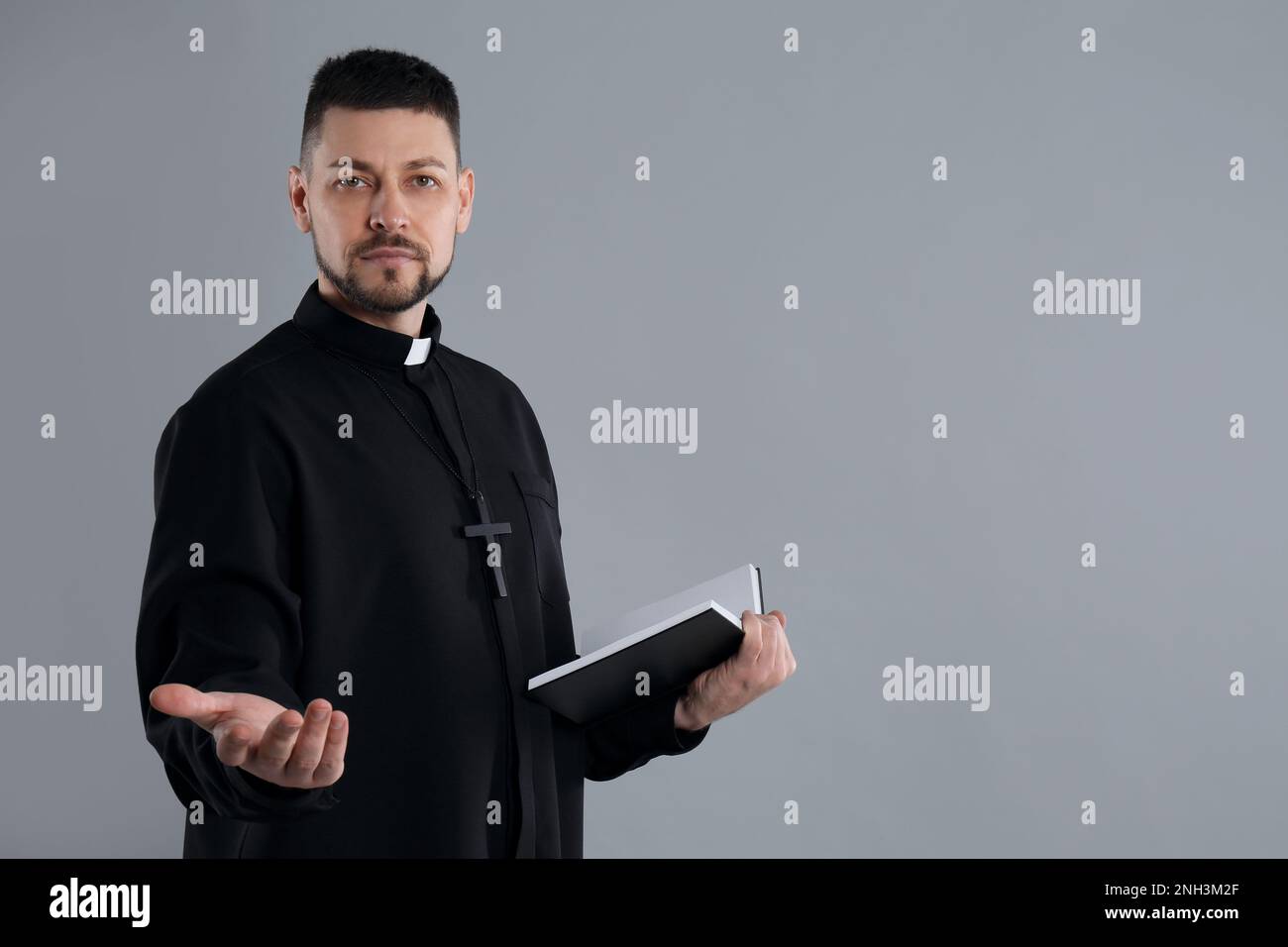 Priest with Bible praying on grey background, space for text Stock ...