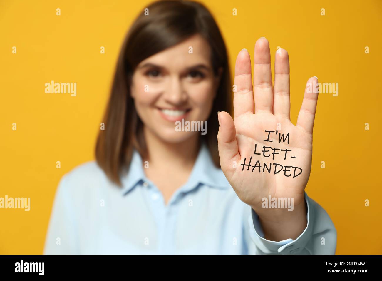 Left-handed woman against yellow background, focus on palm with text ...