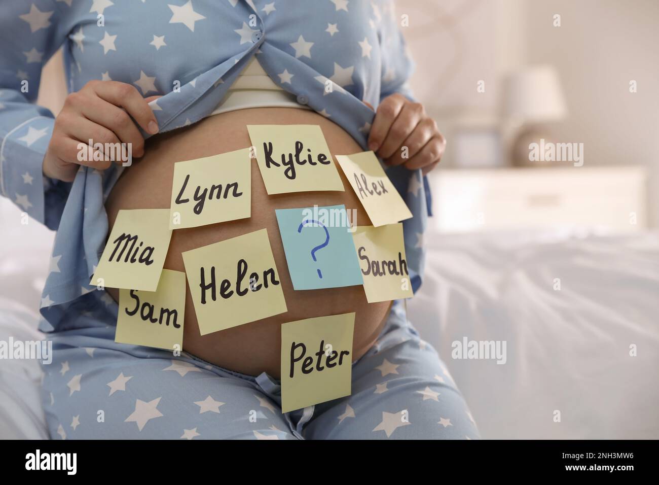 Pregnant woman with different baby names on belly in bedroom, closeup ...