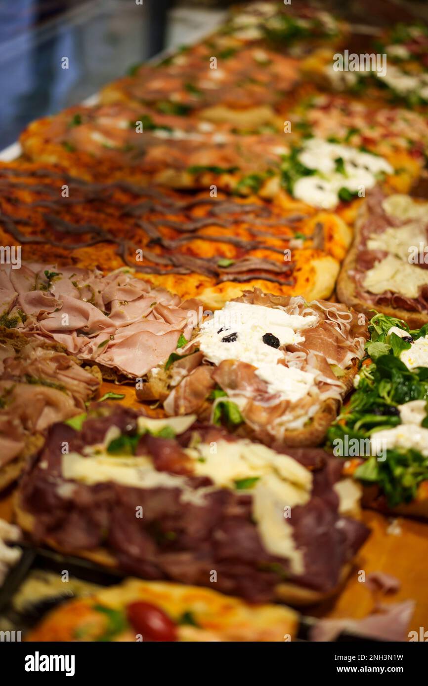 Various flavors pizza cut into square slices on display, in a ...