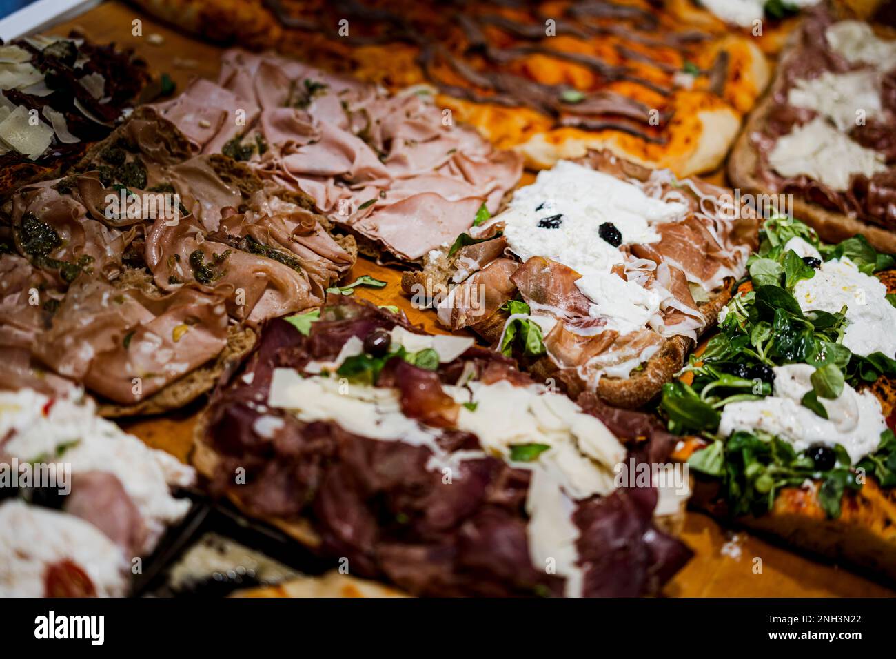 Various flavors pizza cut into square slices on display, in a ...
