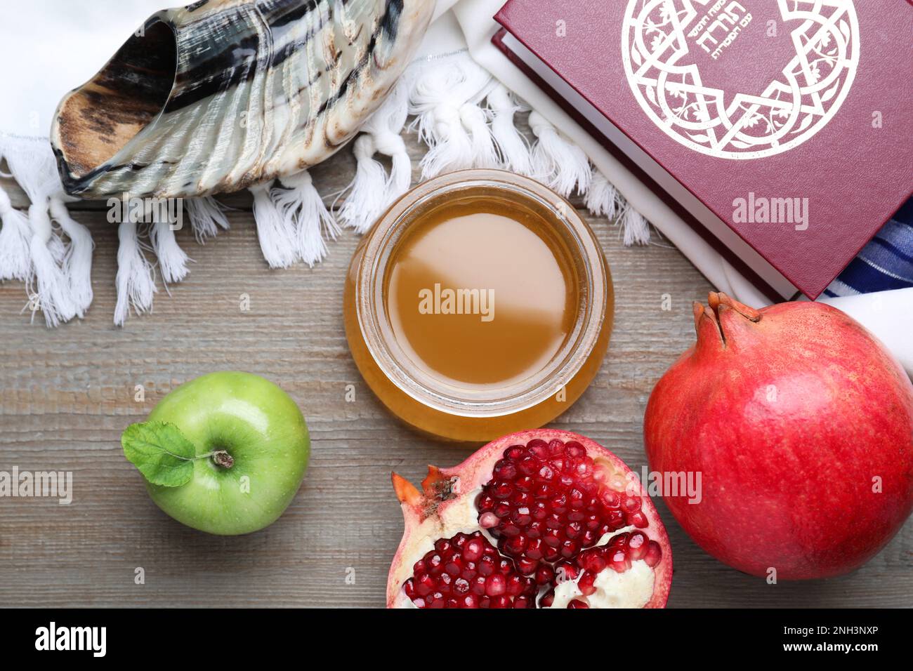 Honey, pomegranate, apples, shofar and Torah on wooden table, flat lay ...