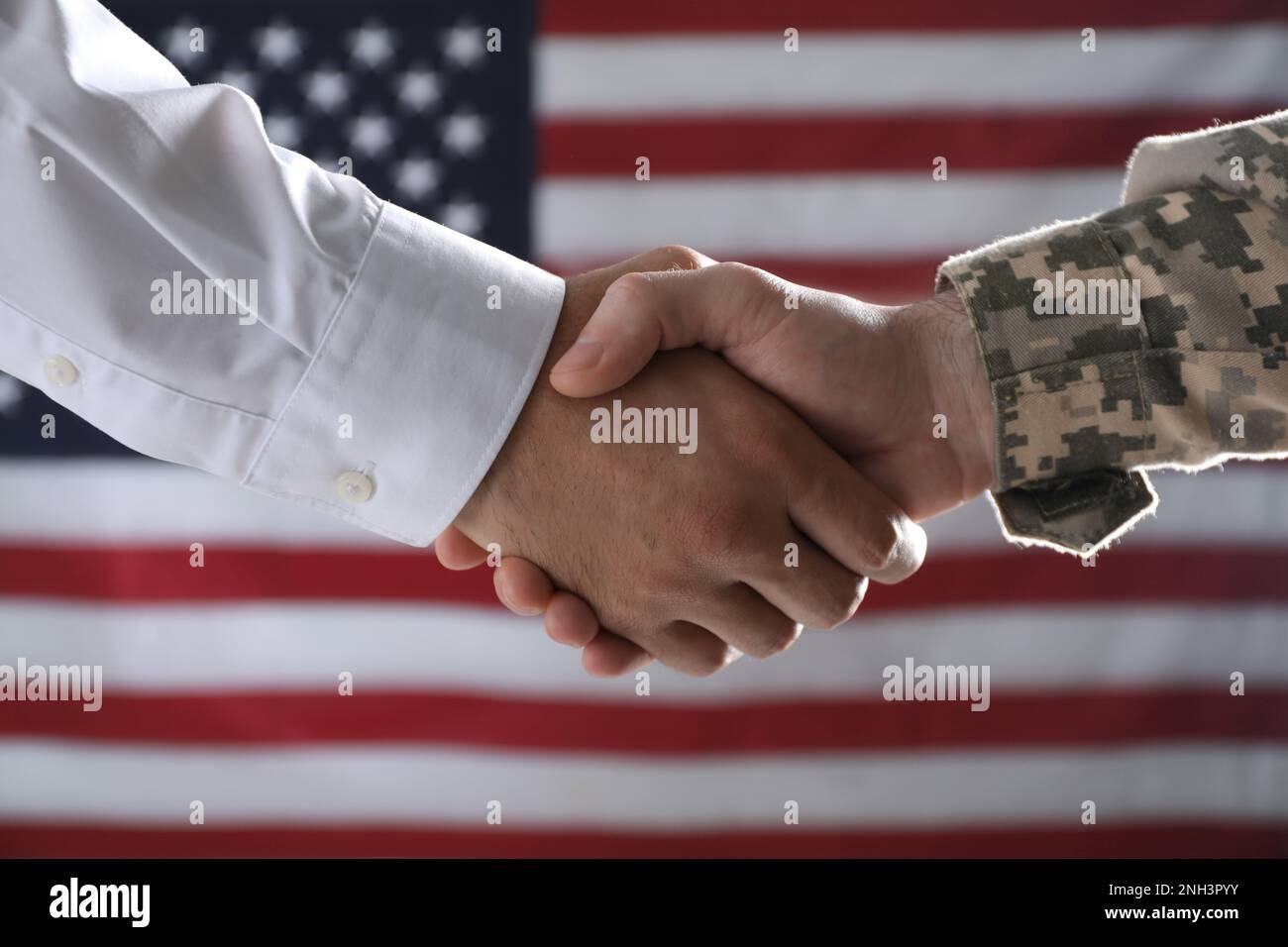 Soldier and businessman shaking hands against flag of USA, closeup ...