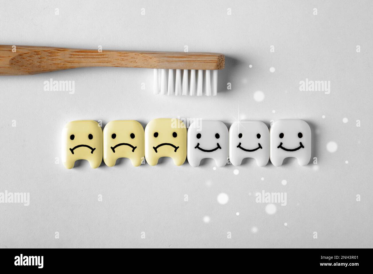 Small plastic teeth with faces and wooden brush on white background ...