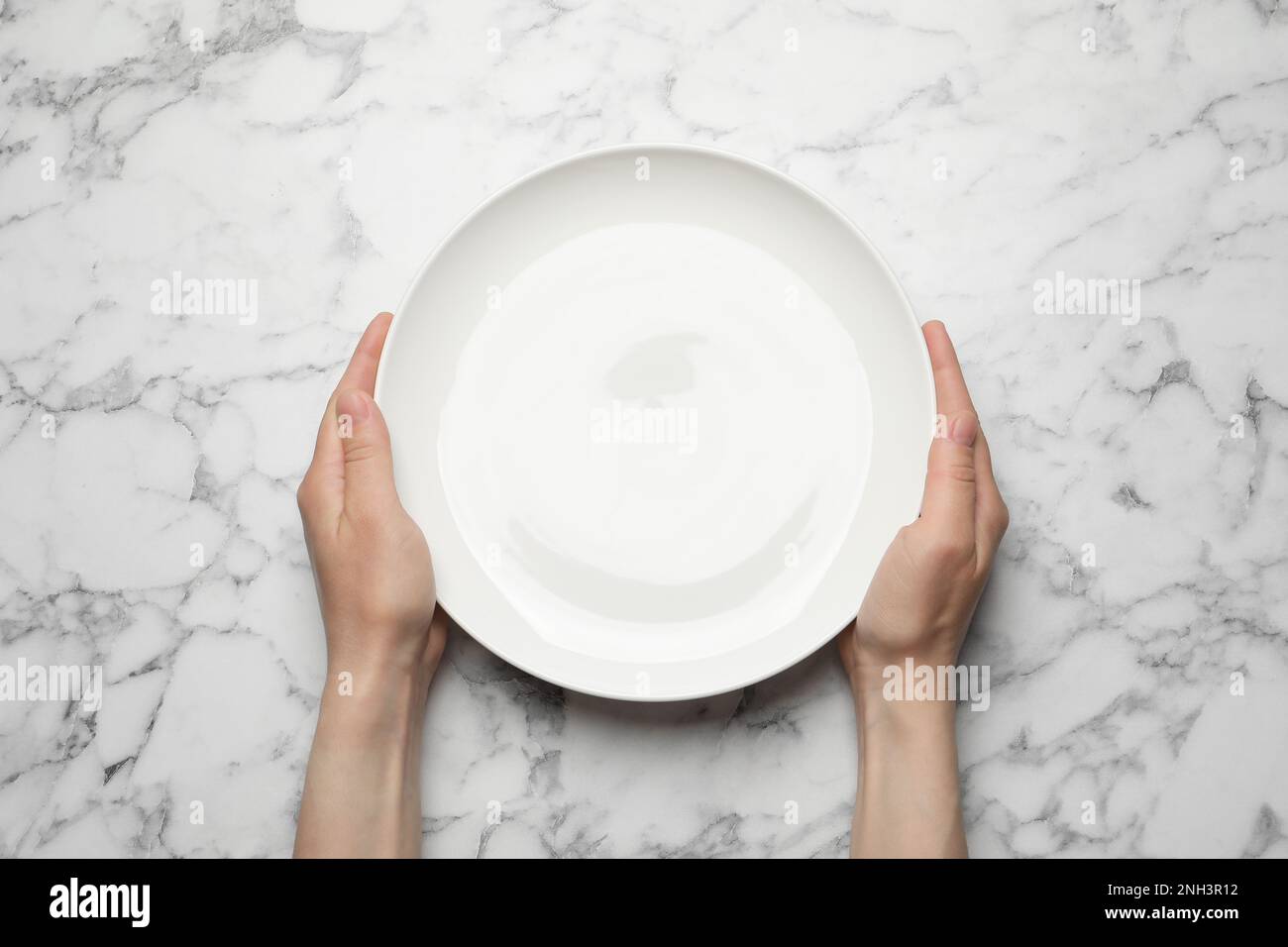 Woman with empty plate at white marble table, top view Stock Photo - Alamy