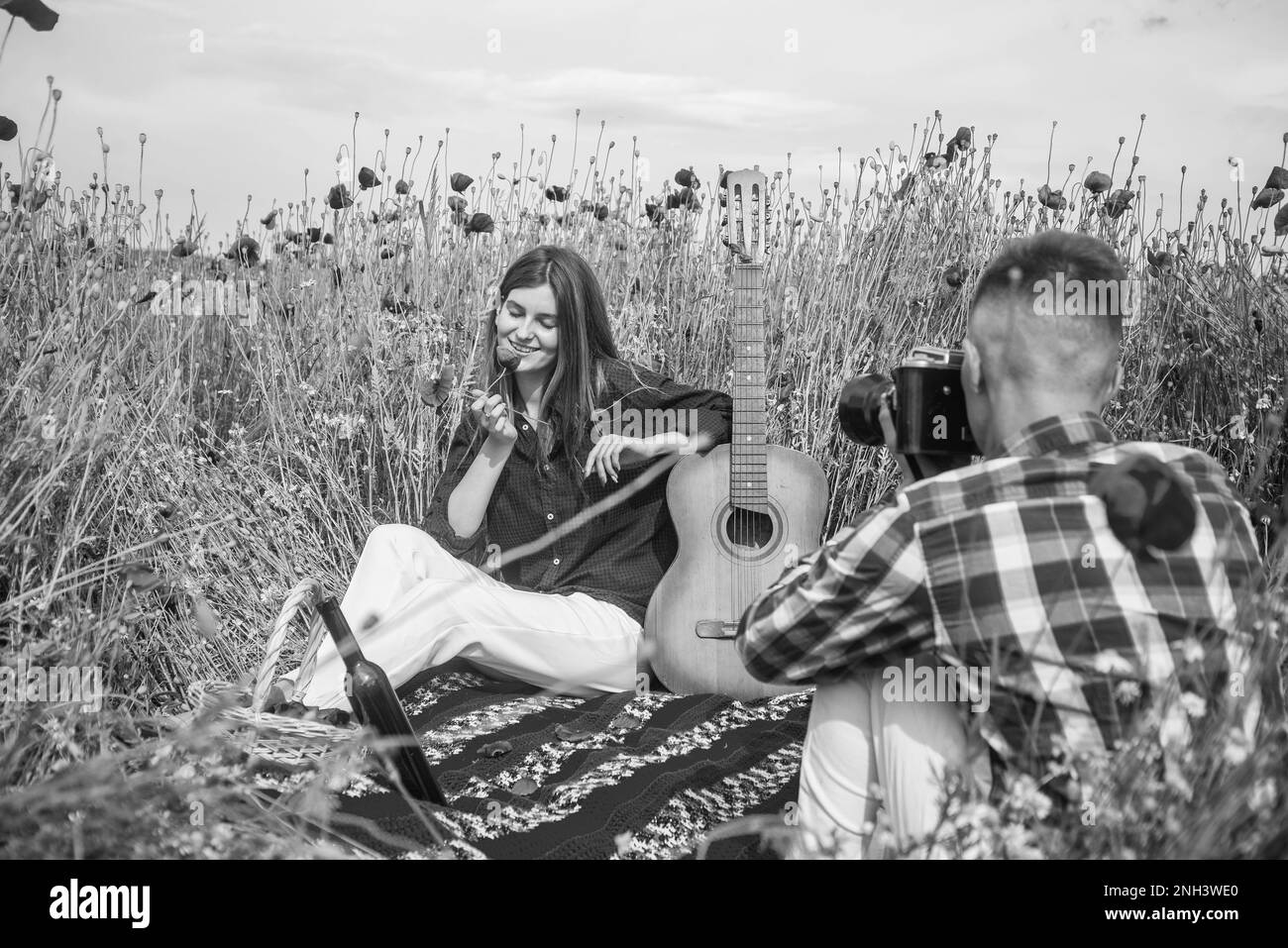 Loving couple photographing on camera during romantic date in poppy ...
