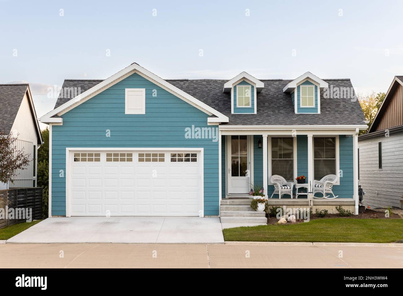 A blue ranch home with a furniture under a covered porch and a two car ...