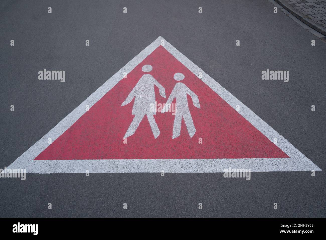 Triangular warning sign on the paved road showing walking pedestrians ...