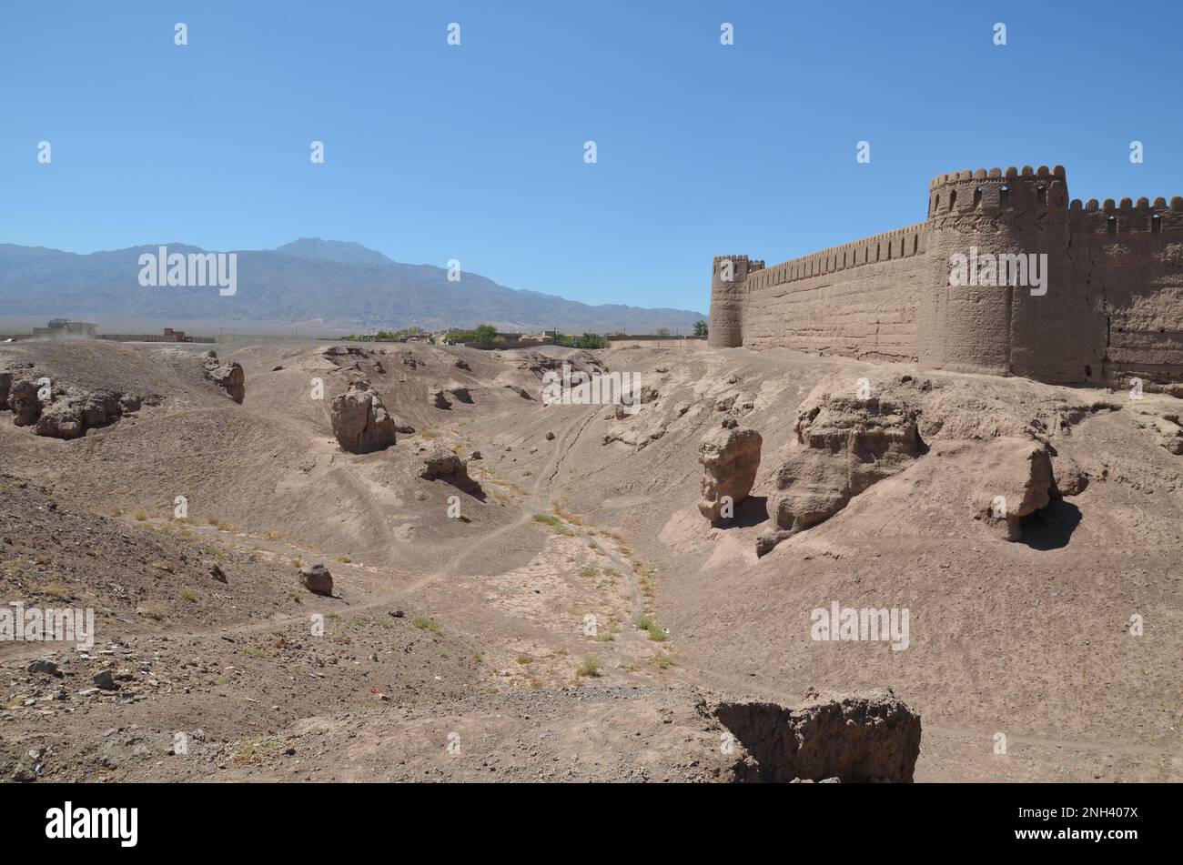 dry desert landscape with mountains and the walls of Rayen Citadel ...