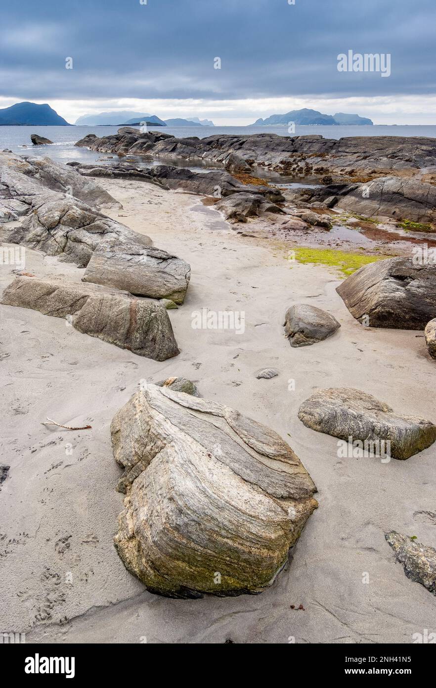 The shoreline is lined with smooth rocks and sandy patches, showcasing ...